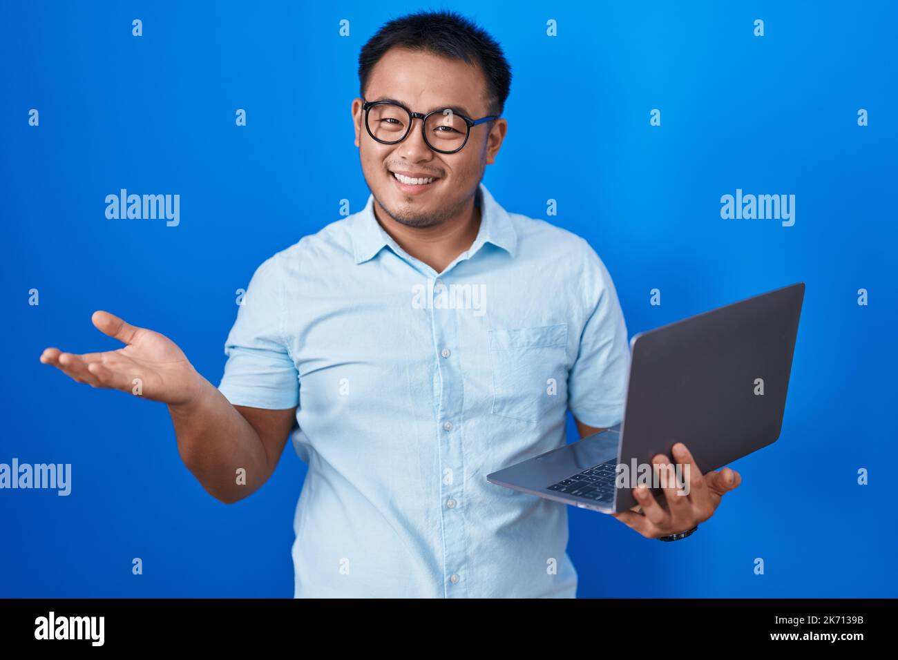 Chinese young man using computer laptop smiling cheerful presenting and ...