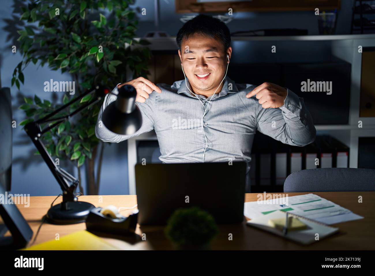Young chinese man working using computer laptop at night looking ...