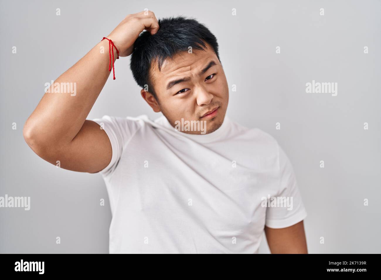 Young chinese man standing over white background confuse and wondering ...