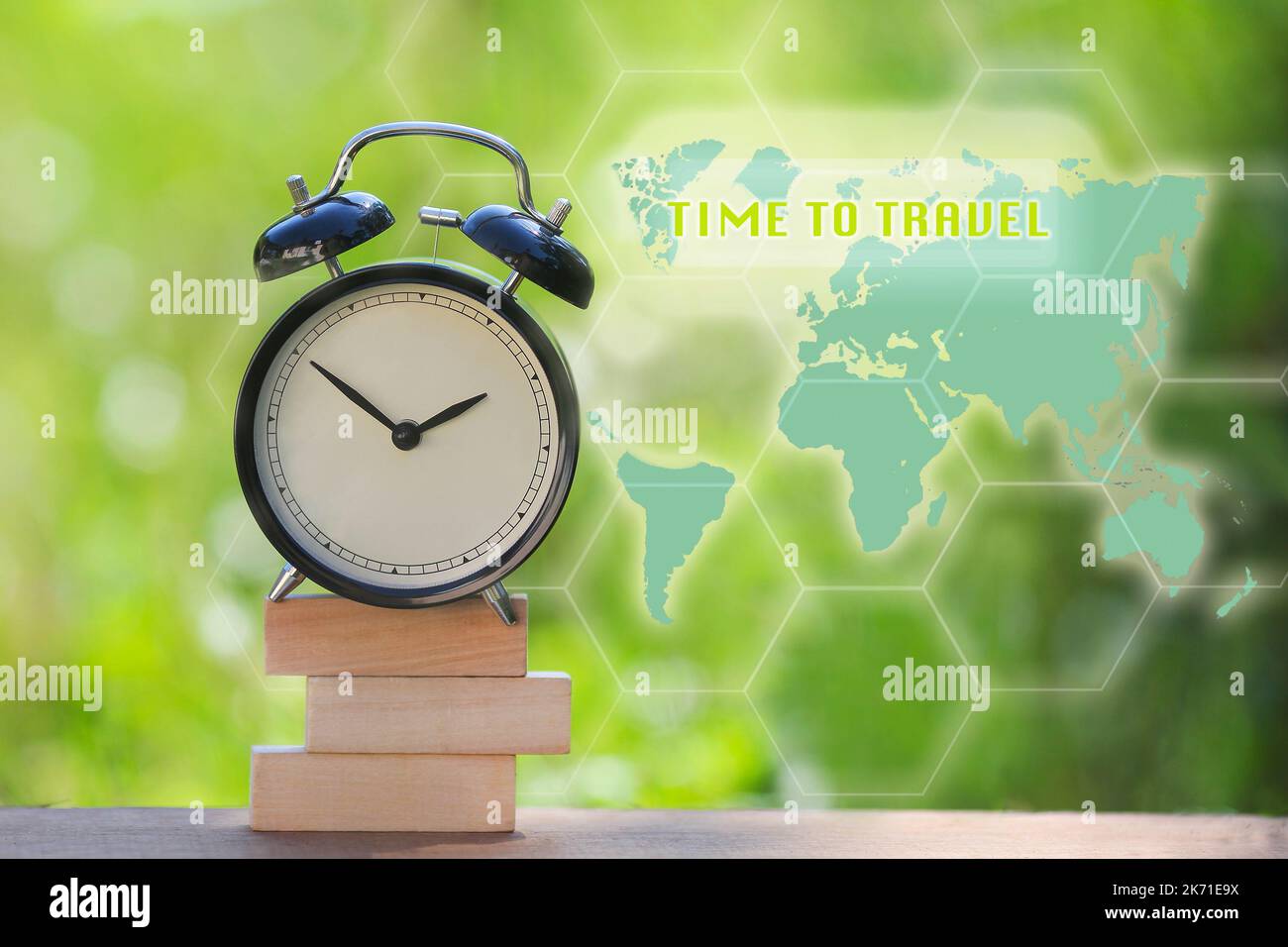 Black alarm clock stacked on wooden bar with shallow DOF green ...