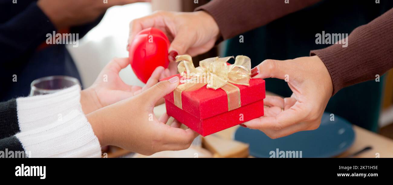 Happy family with daughter giving gift box with father and mother during dinner at home ...