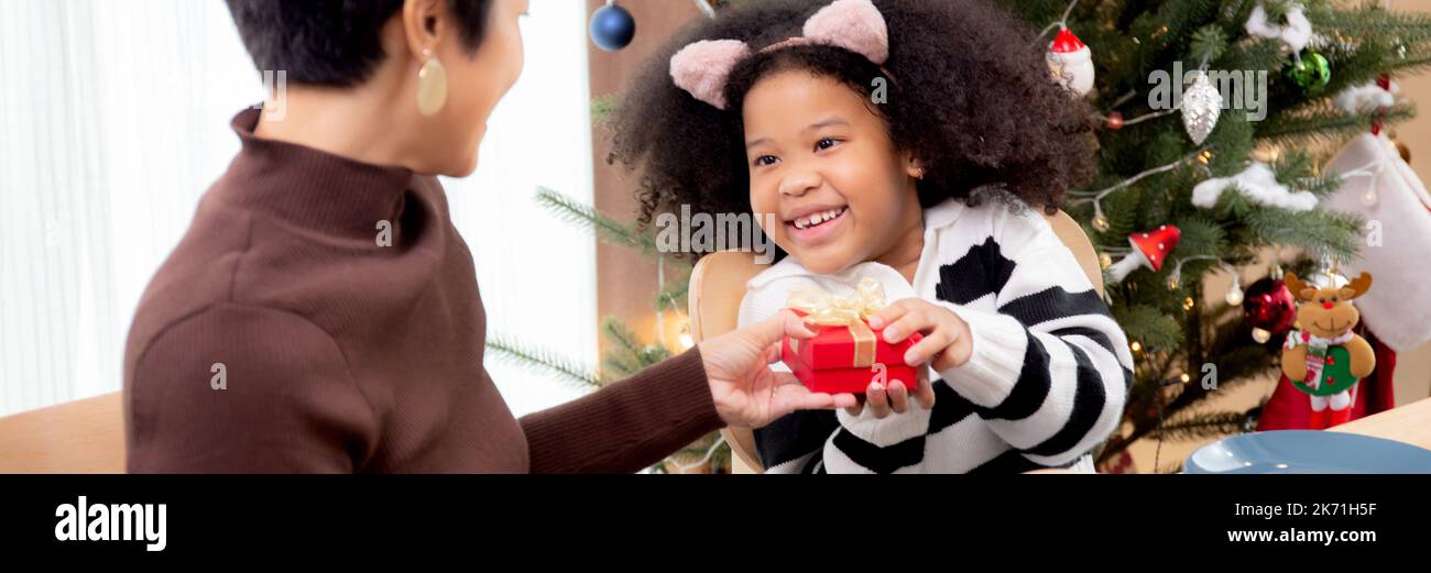 Happy family with mother giving gift box with daughter during dinner at ...
