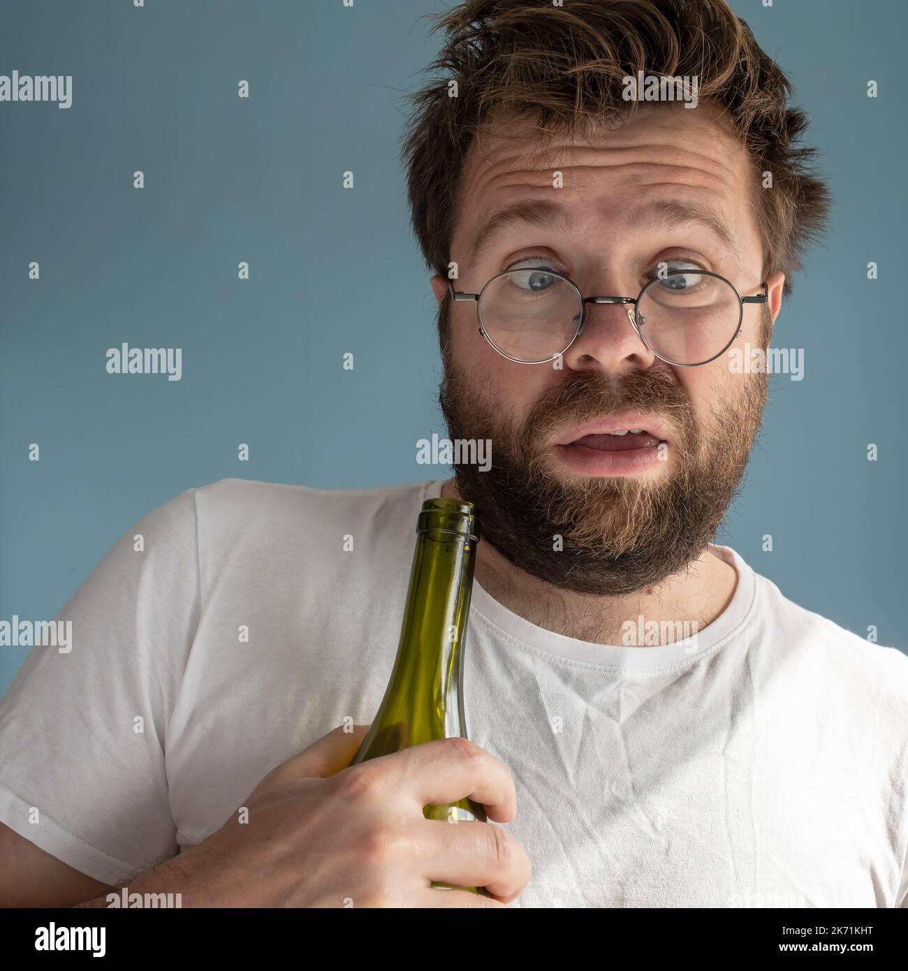 Unshaven man with tousled hair suffers from a hangover, he hugs an ...