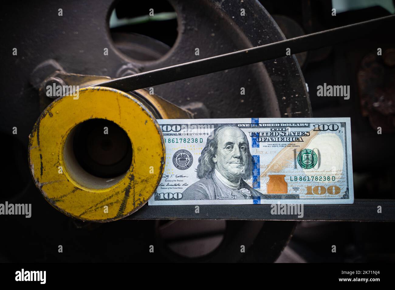 Close-up of a one hundred US dollar bill on a belt driven pulley. Belts ...