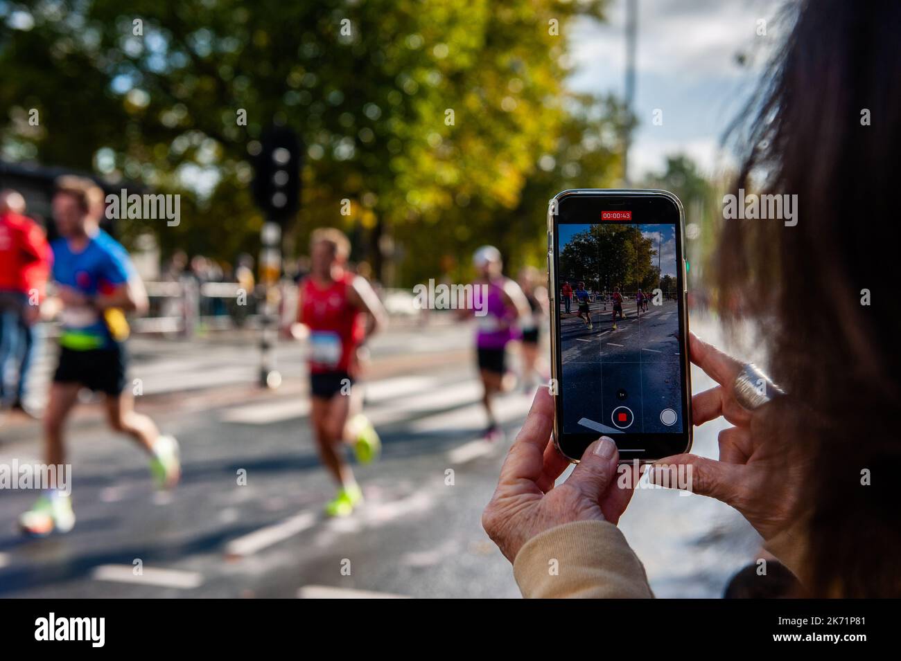 A woman in the audience is seen recording the participants running ...