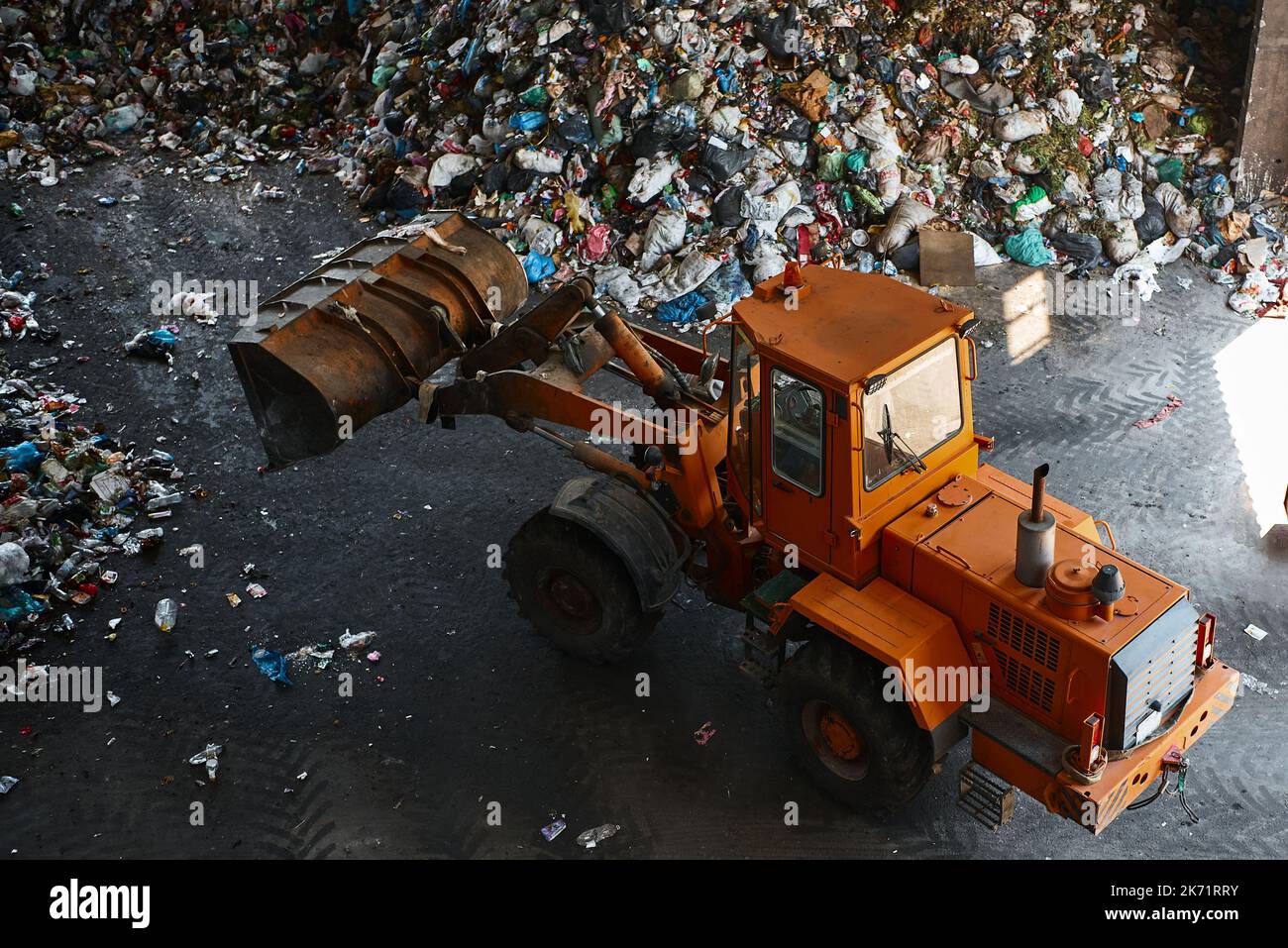 Tractor with scoop and large pile of garbage in storage Stock Photo - Alamy