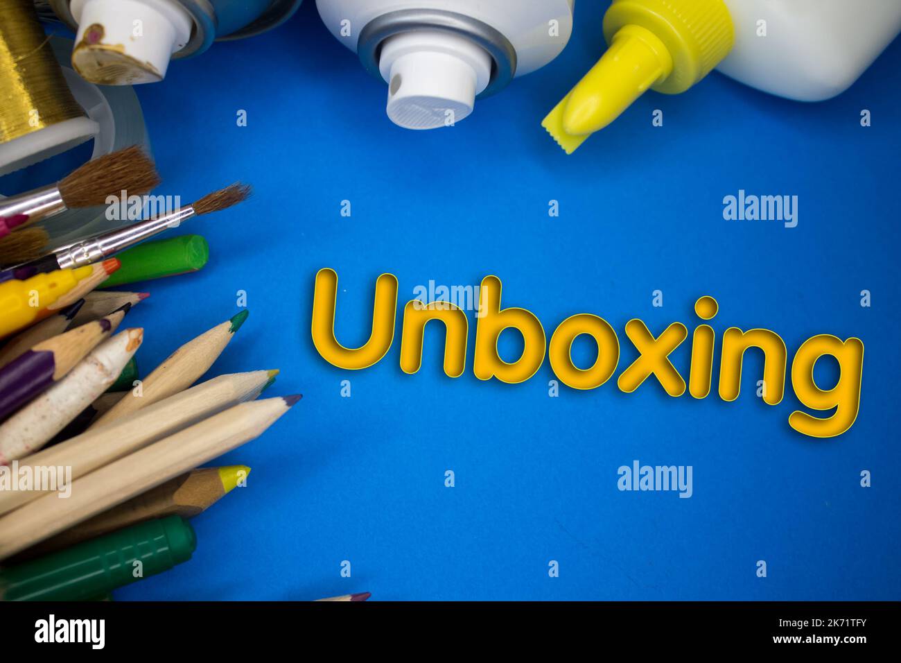 Overhead shot of school supplies with Unboxing text. Brushes, pencils ...