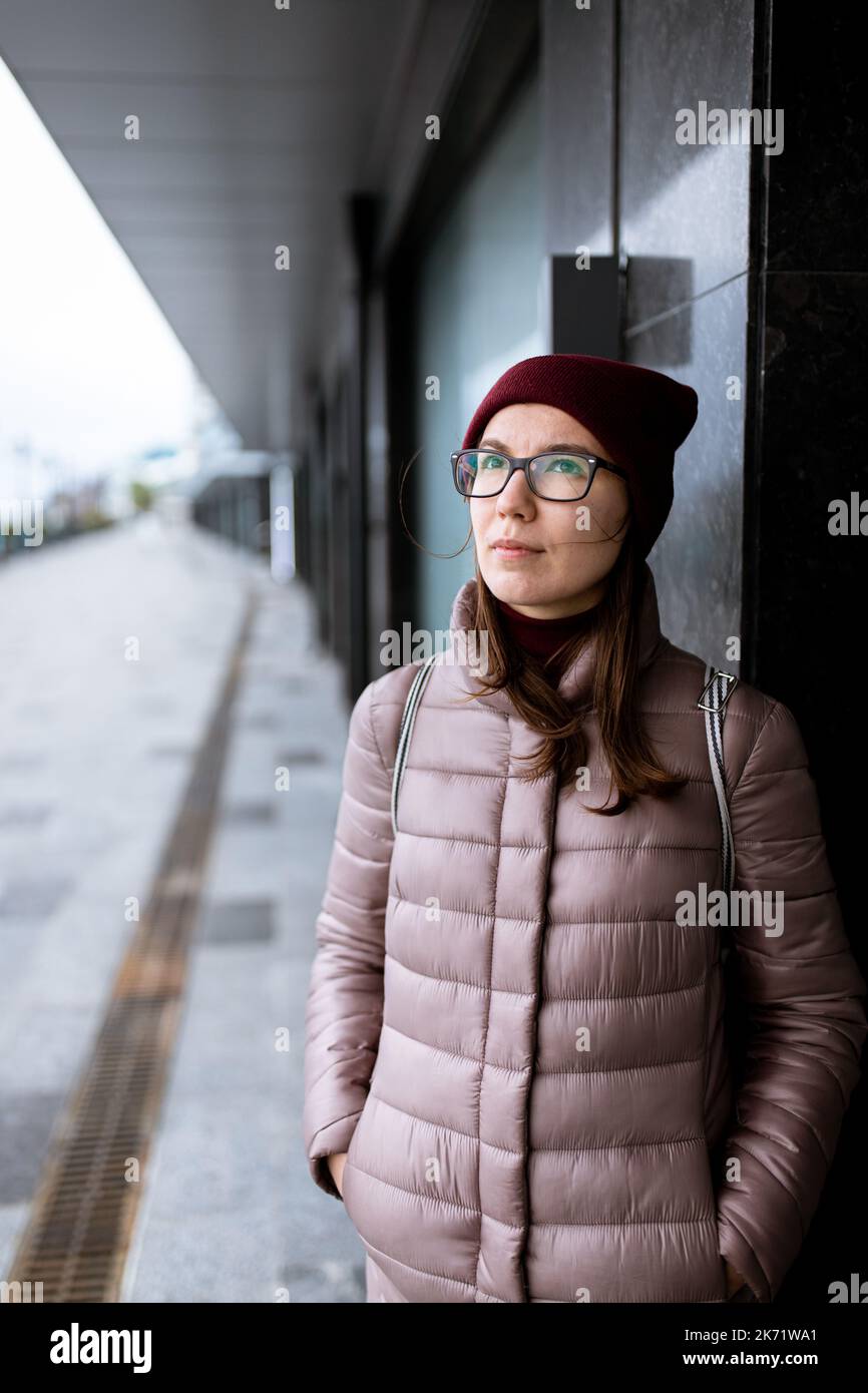 Portrait of a woman in a down jacket and hat in winter in the city of ...