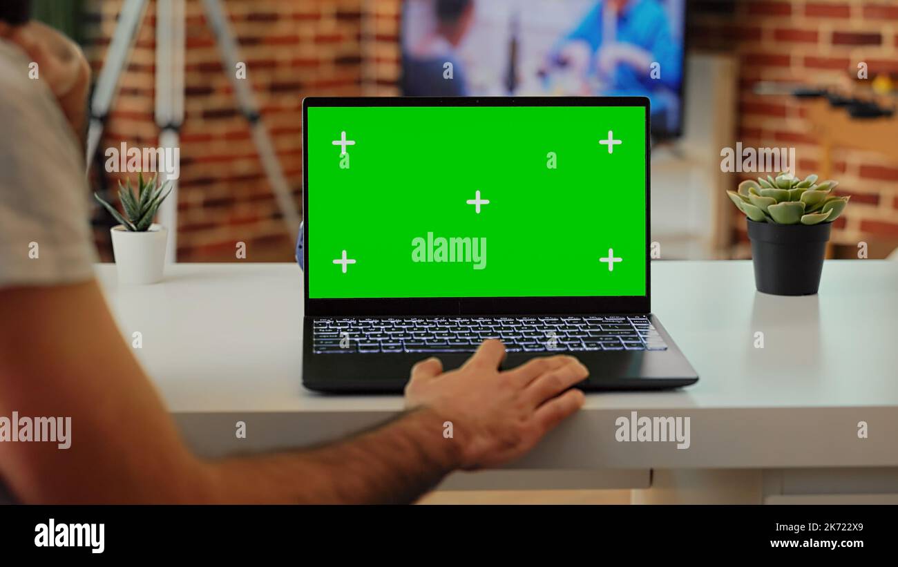 Male employee working with laptop and greenscreen template on display ...
