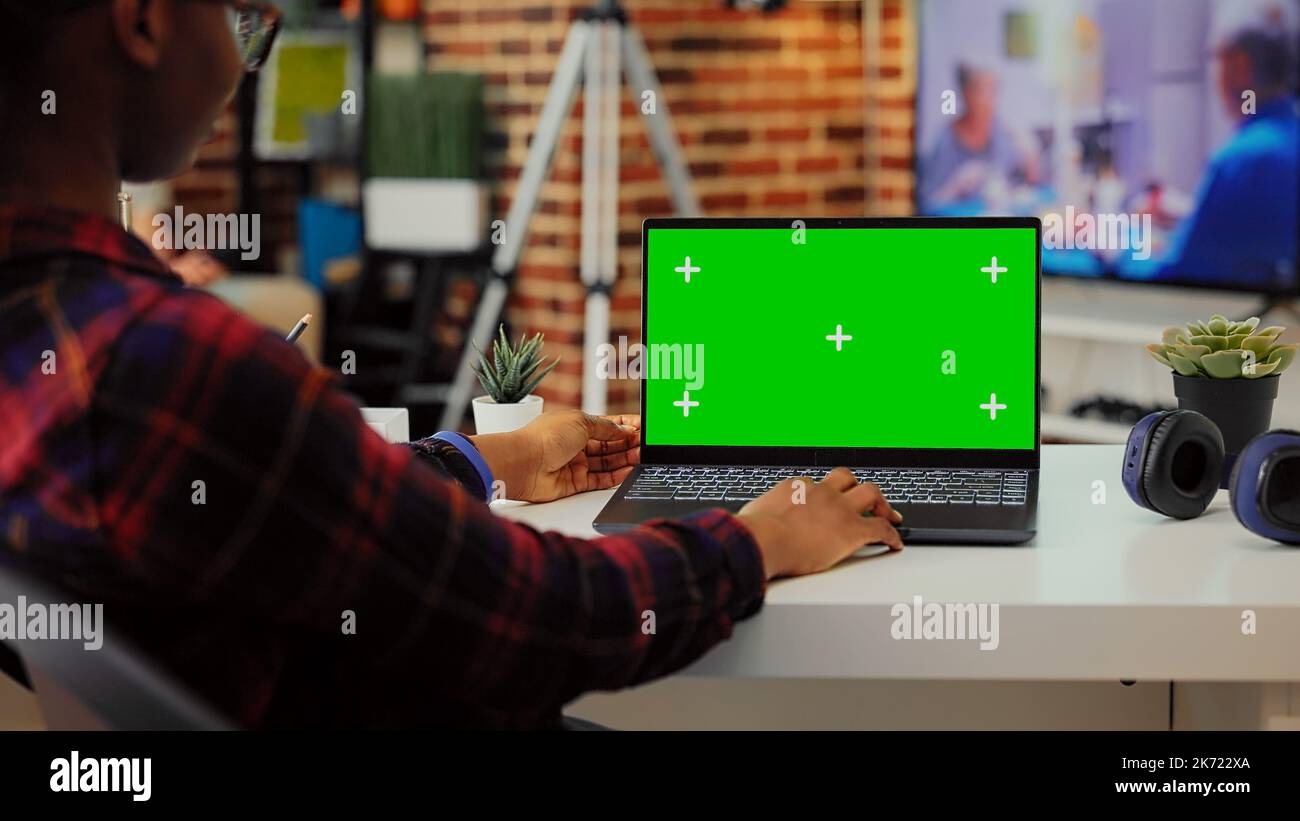 African american student analyzing greenscreen on laptop at desk ...