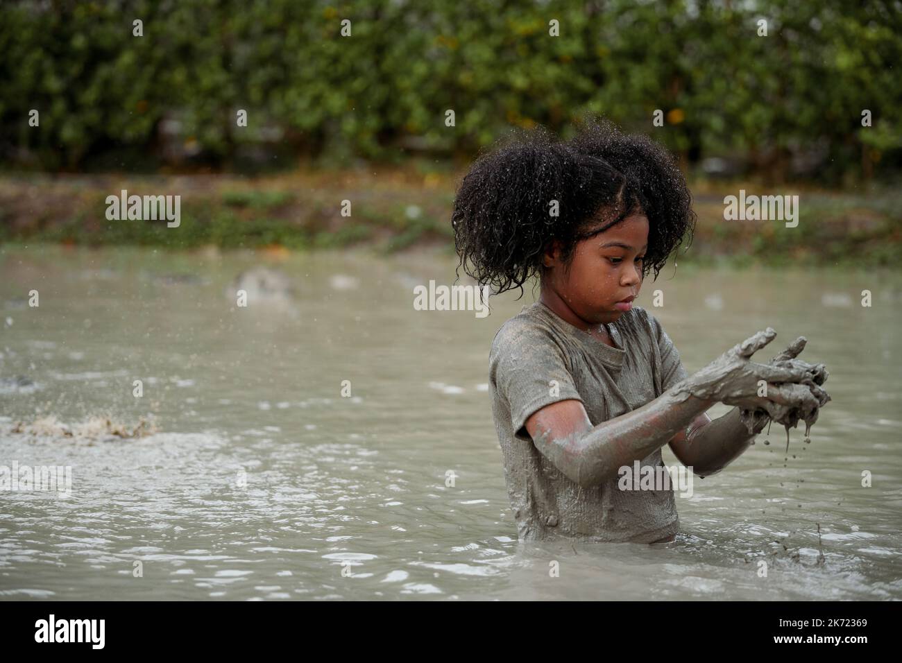 Happy african-american children girl playing in wet mud puddle during ...
