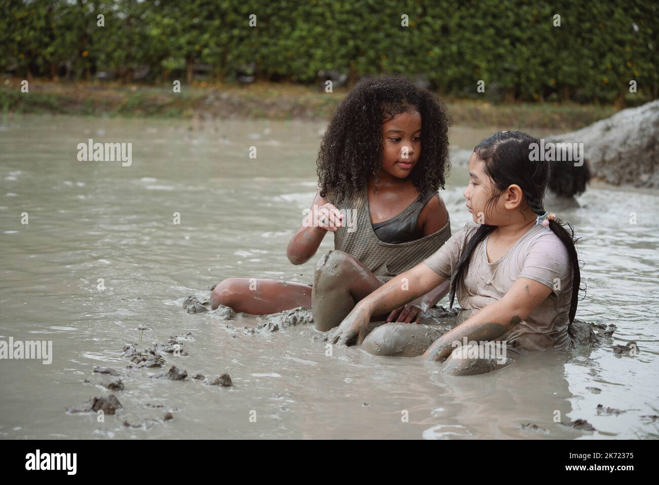 Group of happy children girl playing in wet mud puddle during raining ...