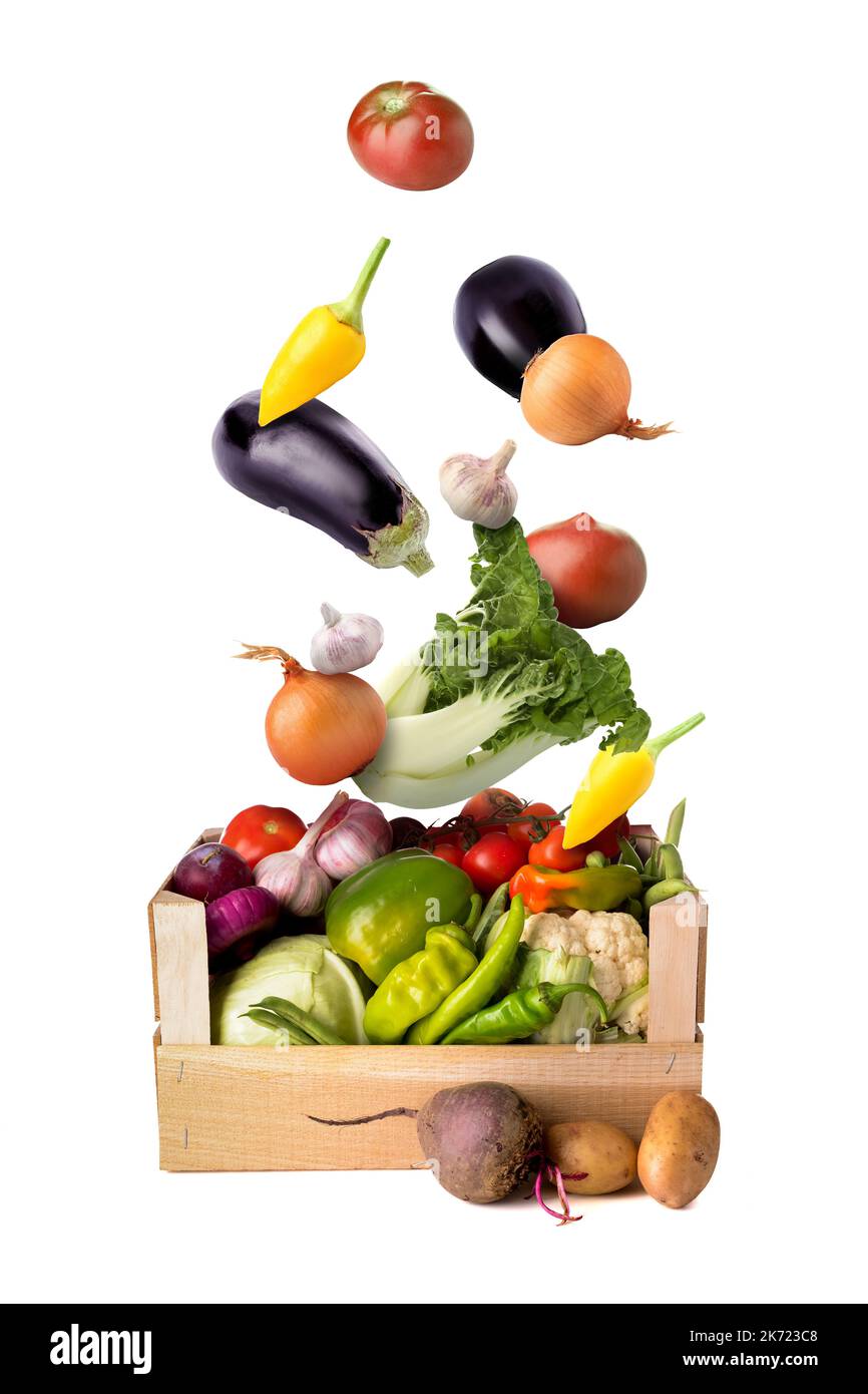 Many healthy vegetables falling into box on white background Stock ...