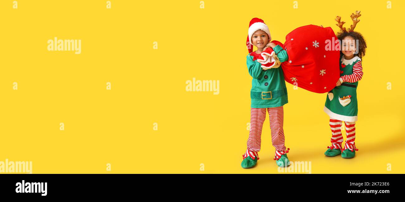 Cute little elves holding Santa bag on yellow background with space for ...