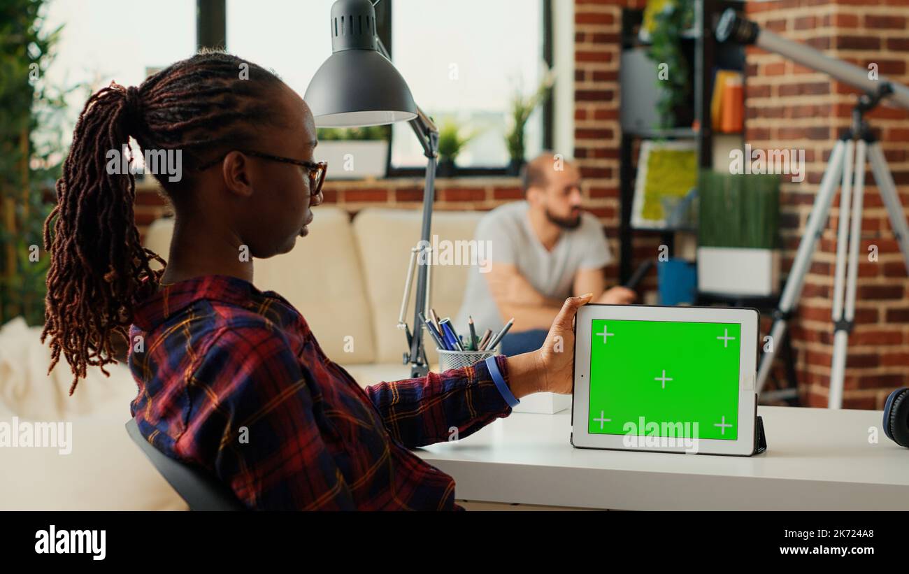 Female freelancer looking at digital tablet with horizontal greenscreen ...
