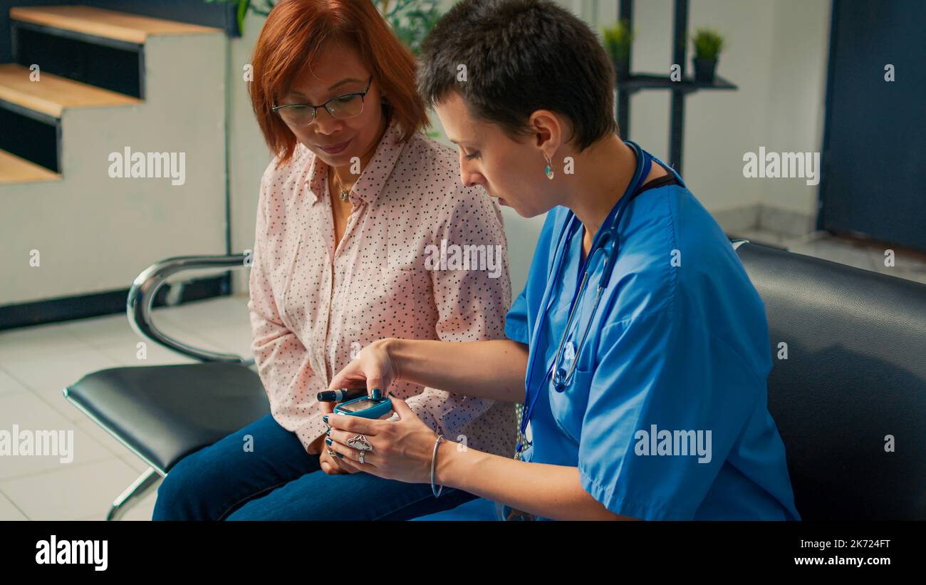Nurse measuring insulin and glucose level with glucometer, doing ...
