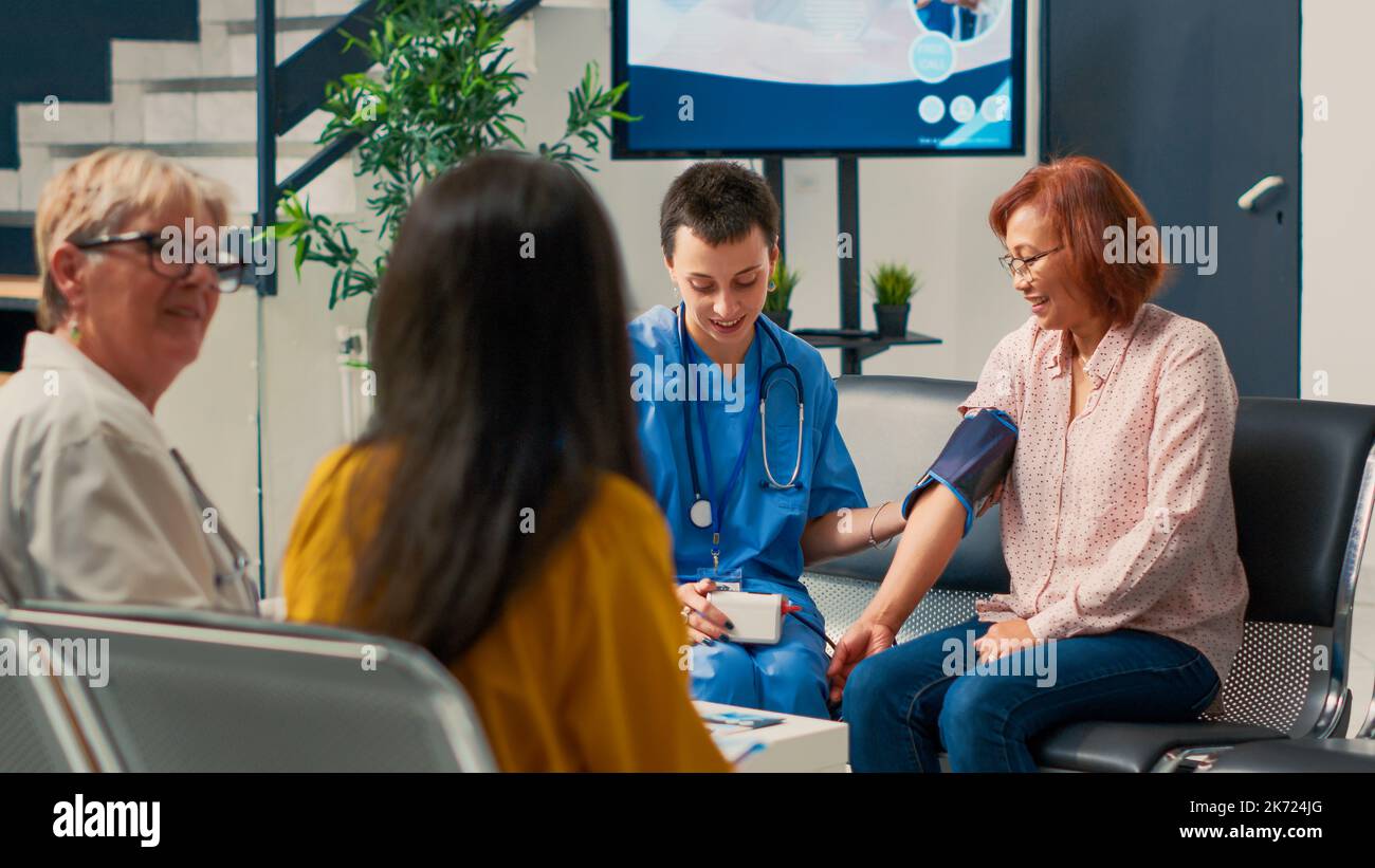 Medical assistant doing cardiac examination with tonometer to measure ...