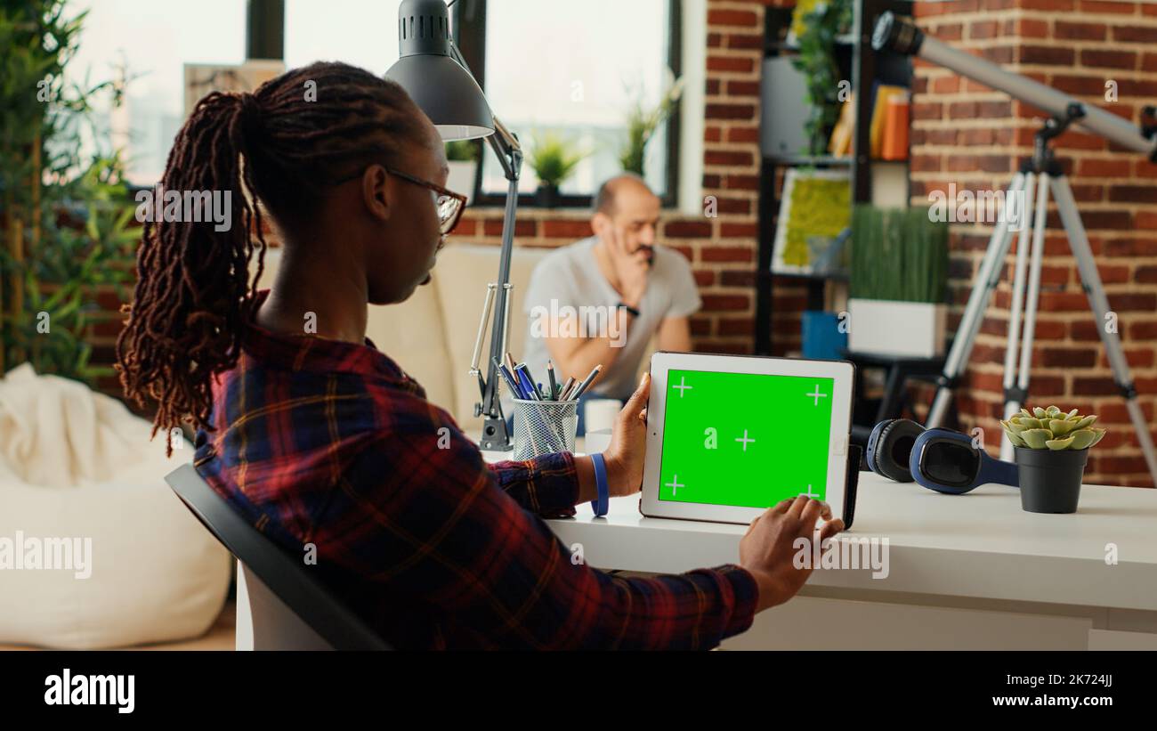 Young adult working with horizontal greenscreen on wireless tablet ...