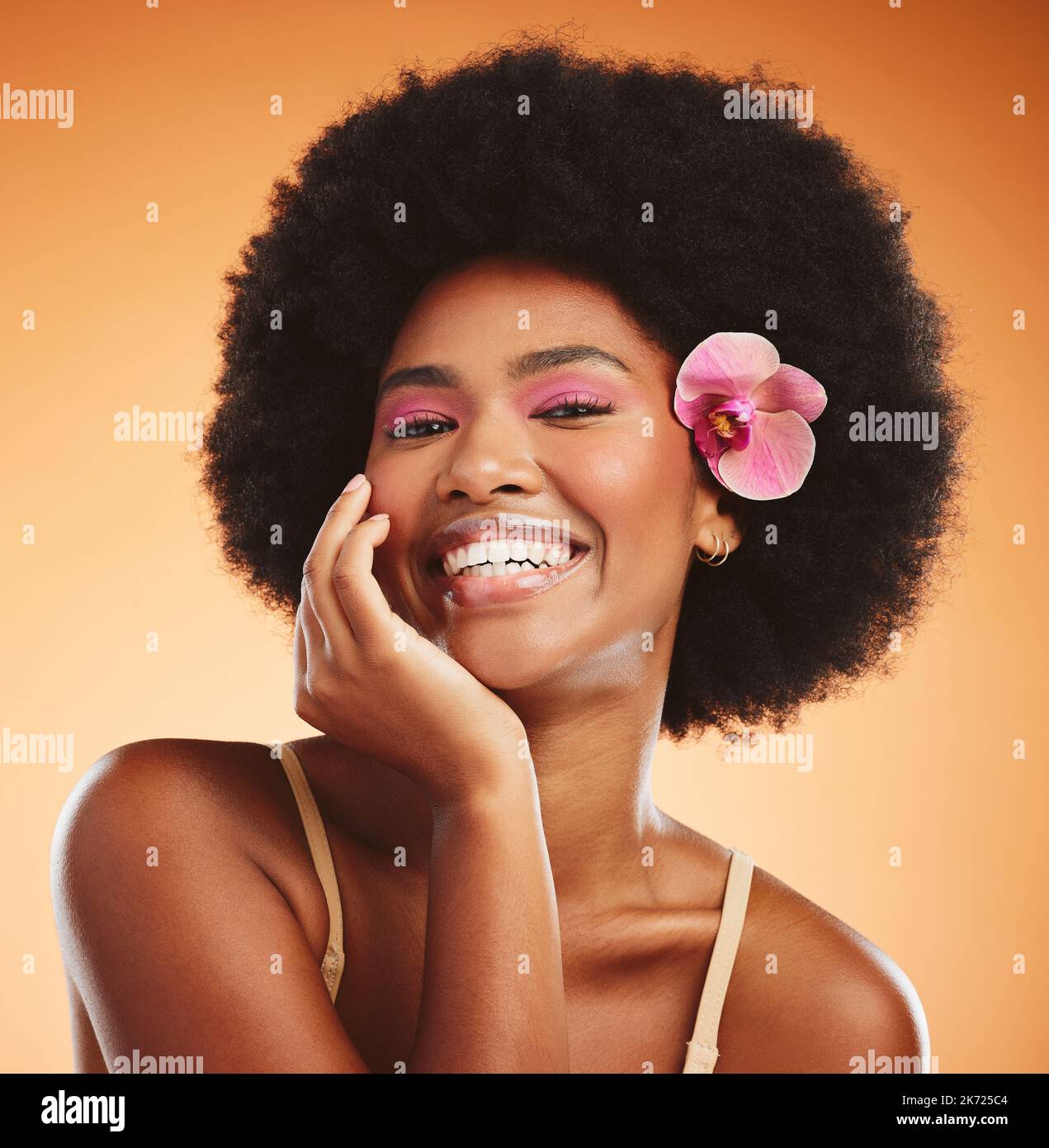 Face, beauty and black woman with flower in afro hair on orange studio ...
