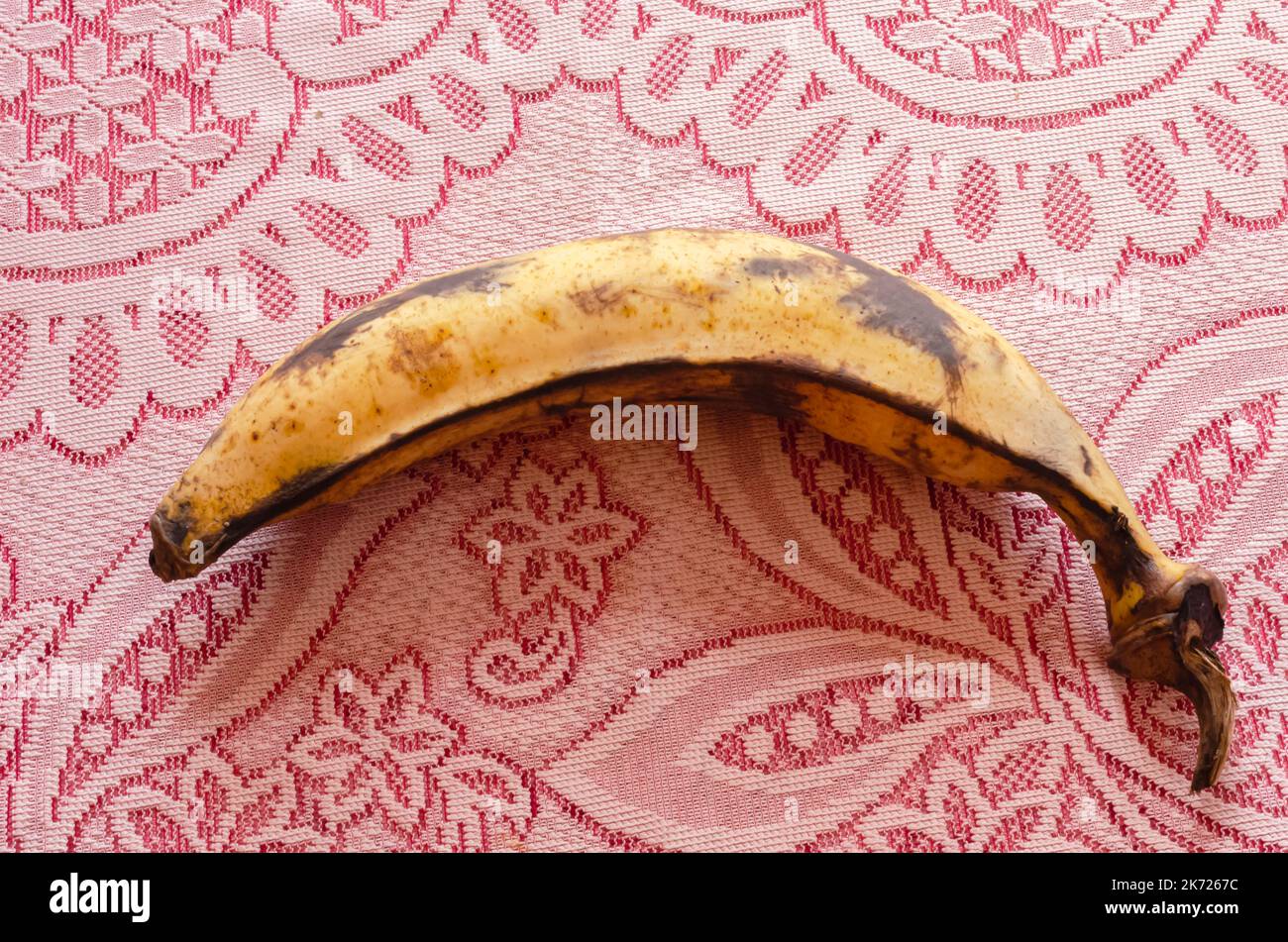 A Spotted yellow ripe plantain is on a red and white tablecloth Stock ...