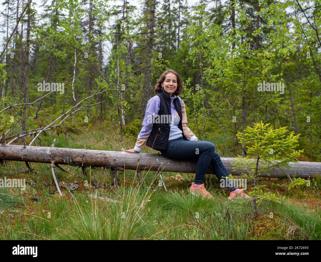 woman sitting on fallen tree in a green forest Stock Photo - Alamy