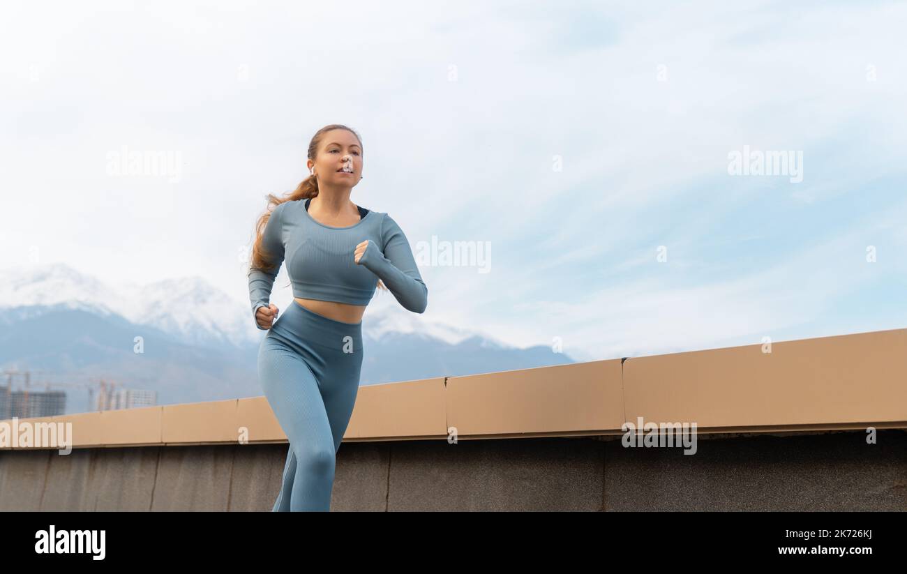 Athletic woman is running on rooftop of parking, garage on sunset ...