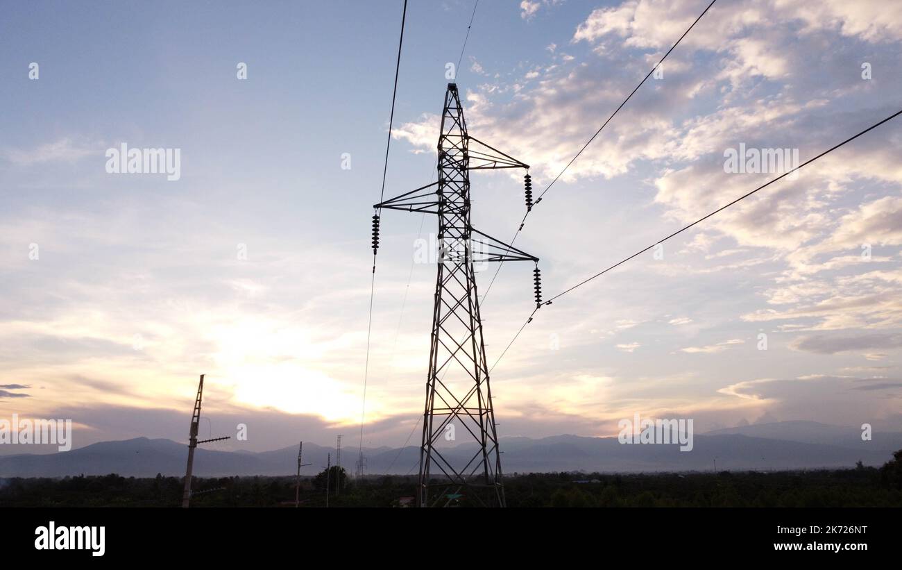 Aerial view of high voltage pylons and wires in the sky at sunset in ...