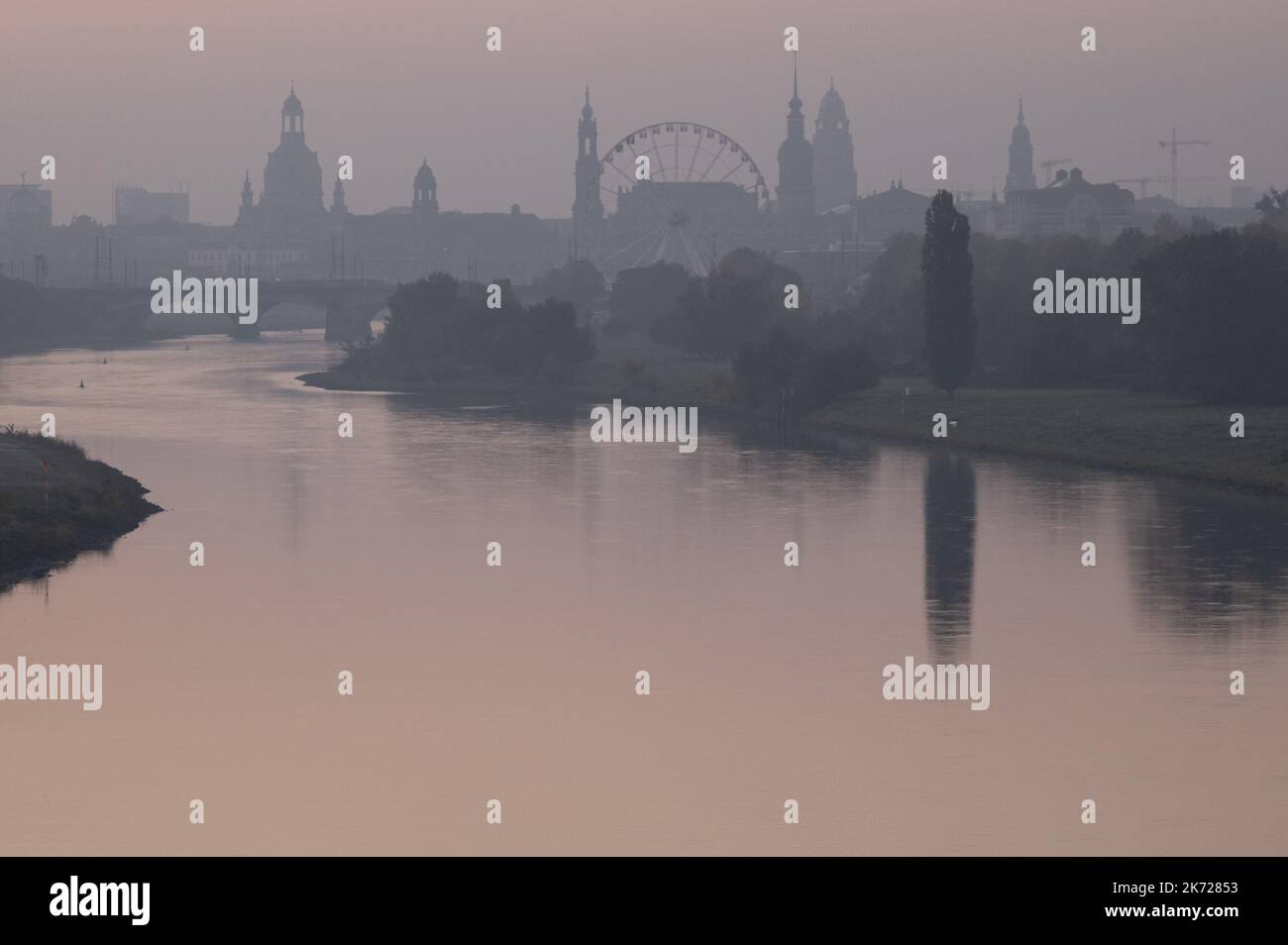Dresden, Germany. 17th Oct, 2022. A Ferris wheel stands at sunrise against the backdrop of the ...