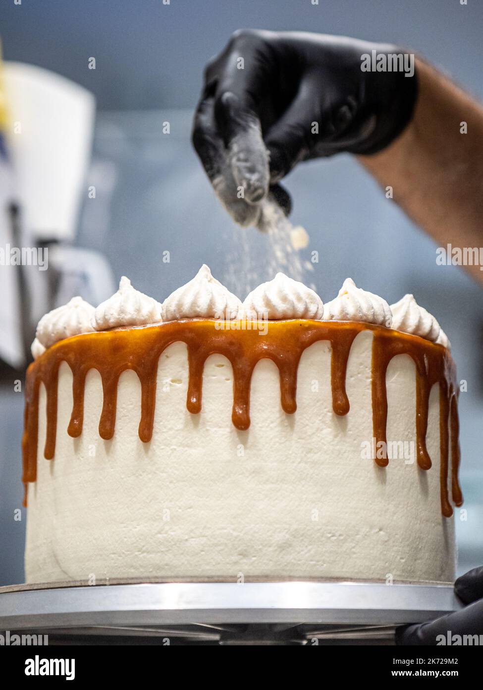 cake desginer topping a sweet icing caramel cake Stock Photo - Alamy