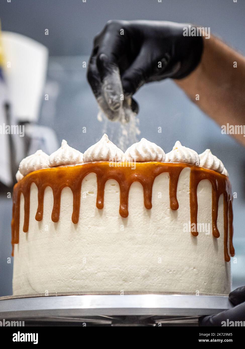 cake desginer topping a sweet icing caramel cake Stock Photo - Alamy