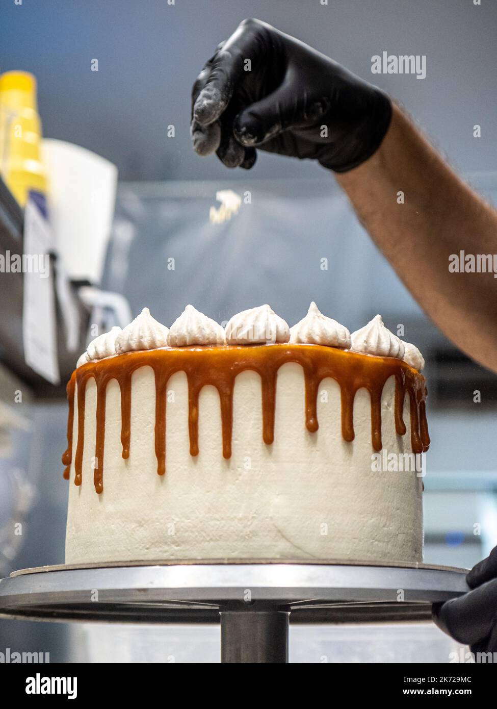 cake desginer topping a sweet icing caramel cake Stock Photo - Alamy