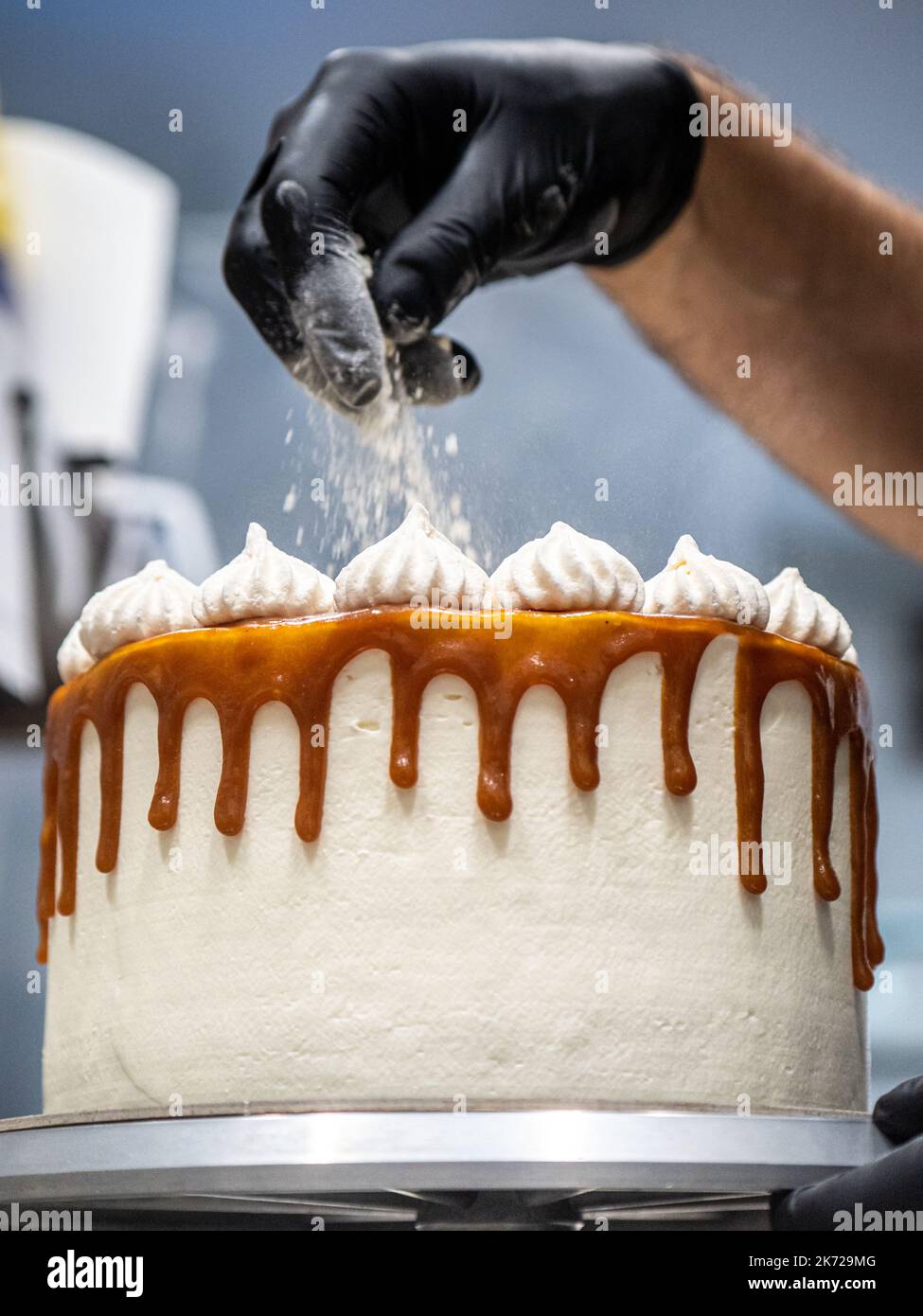 cake desginer topping a sweet icing caramel cake Stock Photo - Alamy