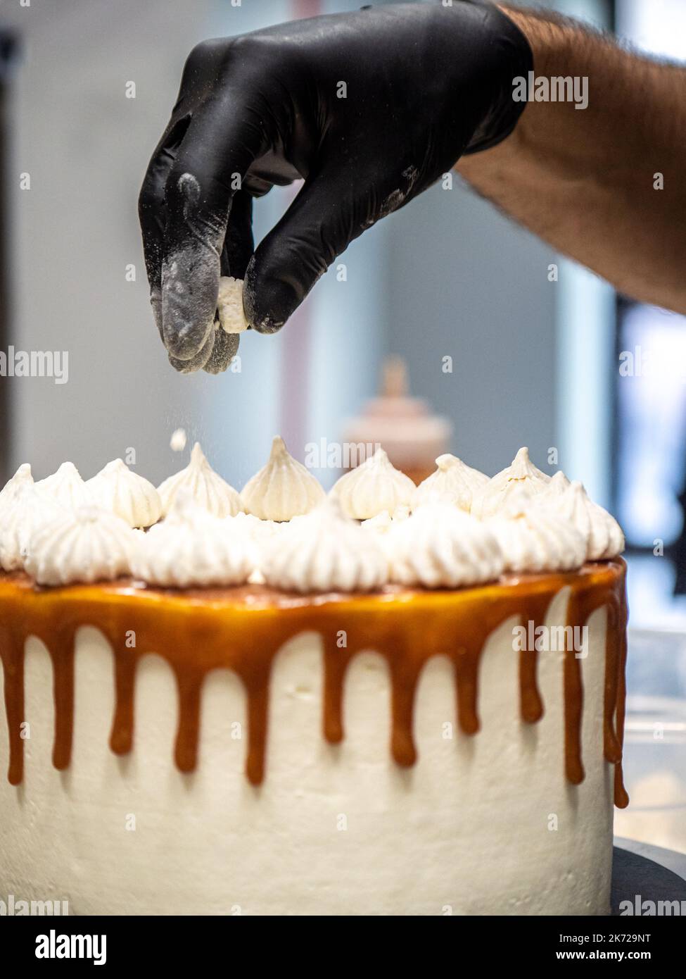 cake desginer topping a sweet icing caramel cake Stock Photo - Alamy