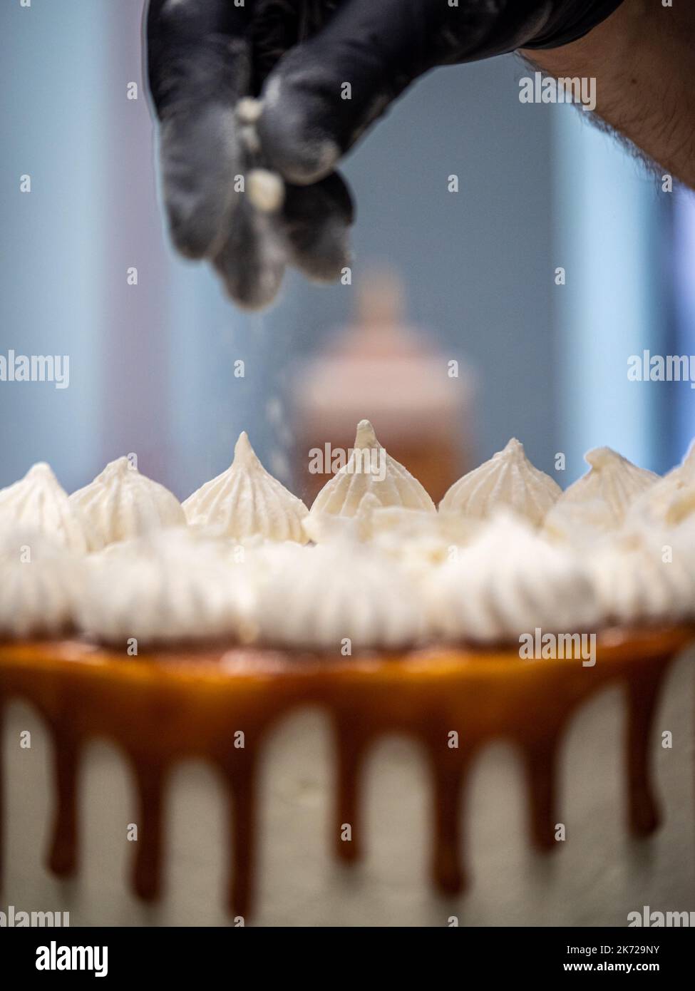 cake desginer topping a sweet icing caramel cake Stock Photo - Alamy