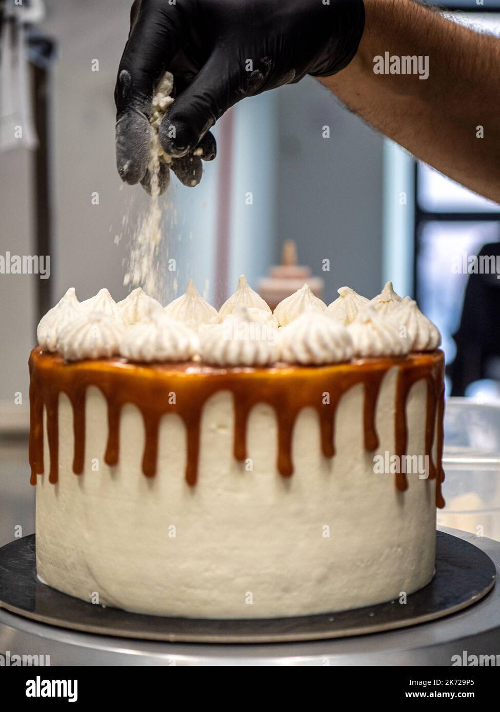 cake desginer topping a sweet icing caramel cake Stock Photo - Alamy