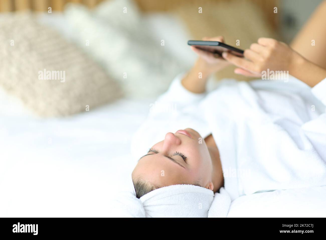 Woman lying on the bed after showering using smart phone at home Stock ...