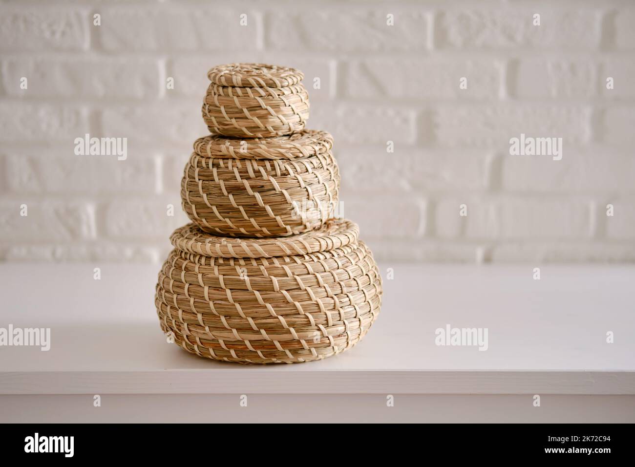 Close-up of three round stream box with lid on white table. Wicker ...