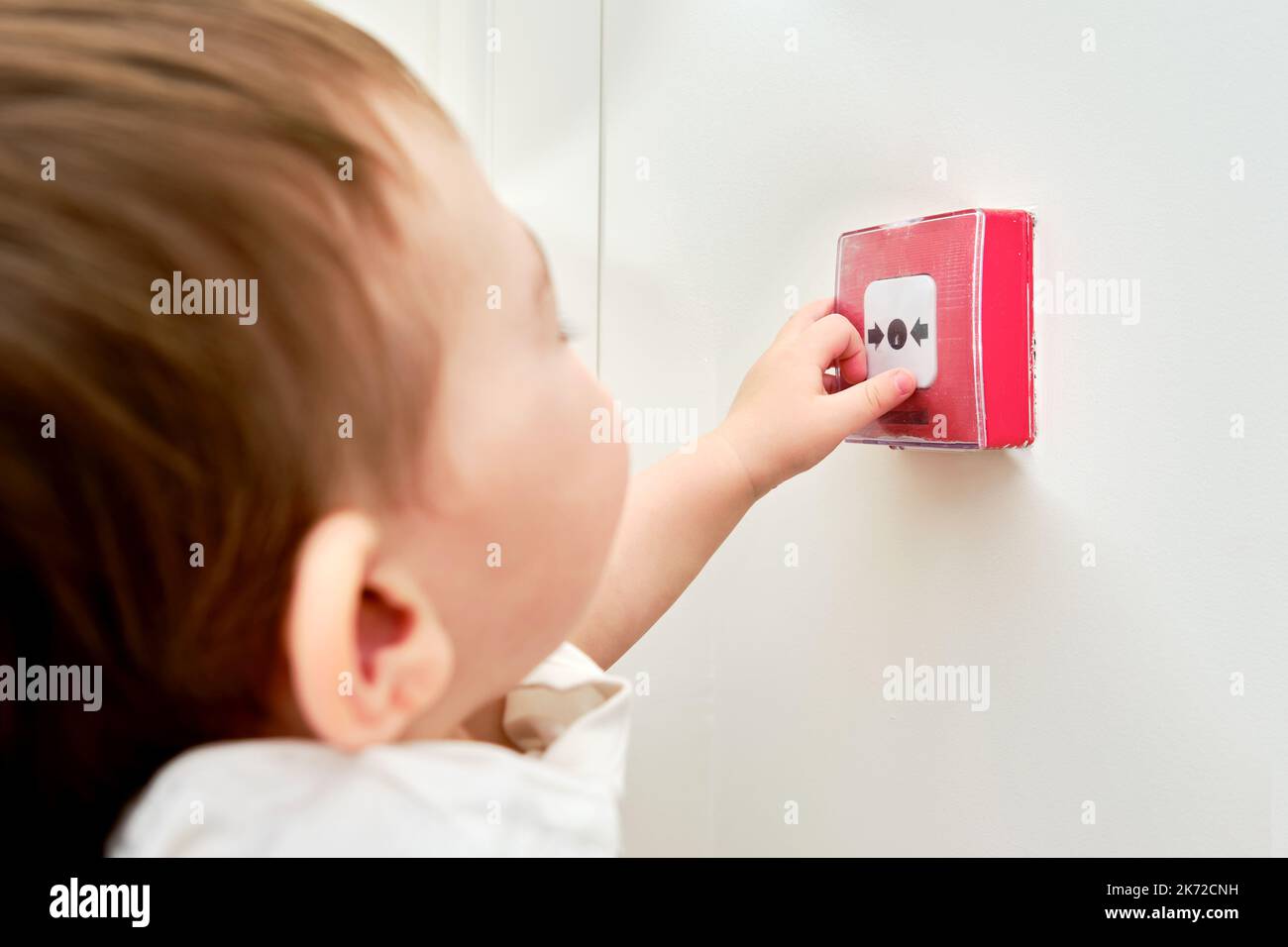 Toddler baby reaches for the fire alarm, child s hand turns on the call ...