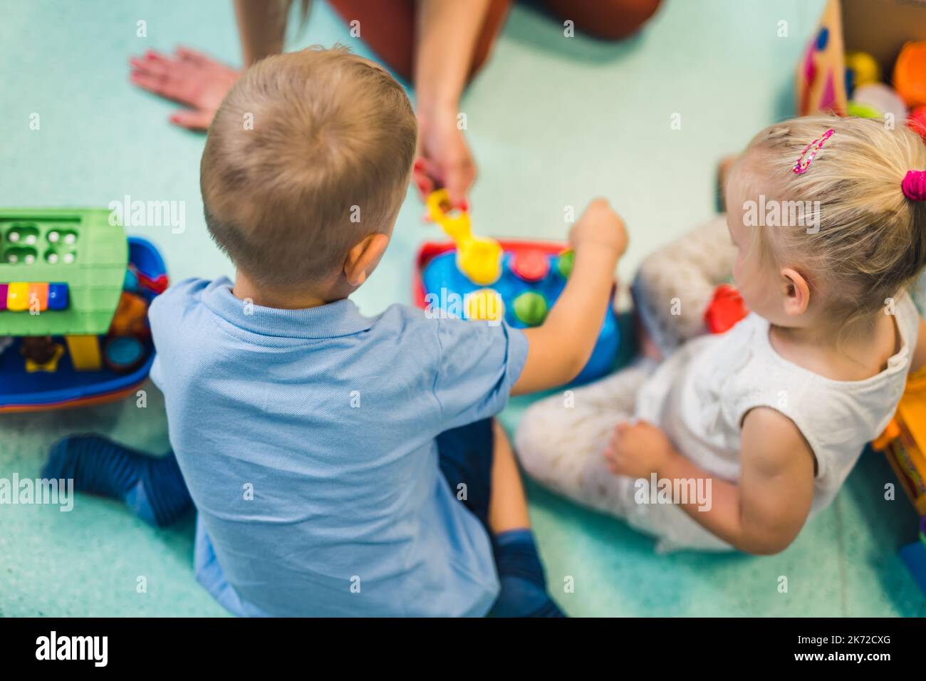 little children playing with toys in the nursery, indoor kindergarten ...