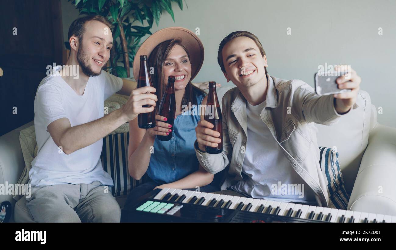 Happy attractive musicians are taking selfie with beer bottles sitting ...
