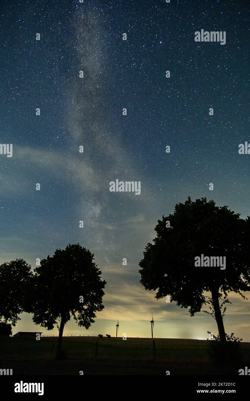 Milky Way with trees and wind wheels in Germany Stock Photo - Alamy