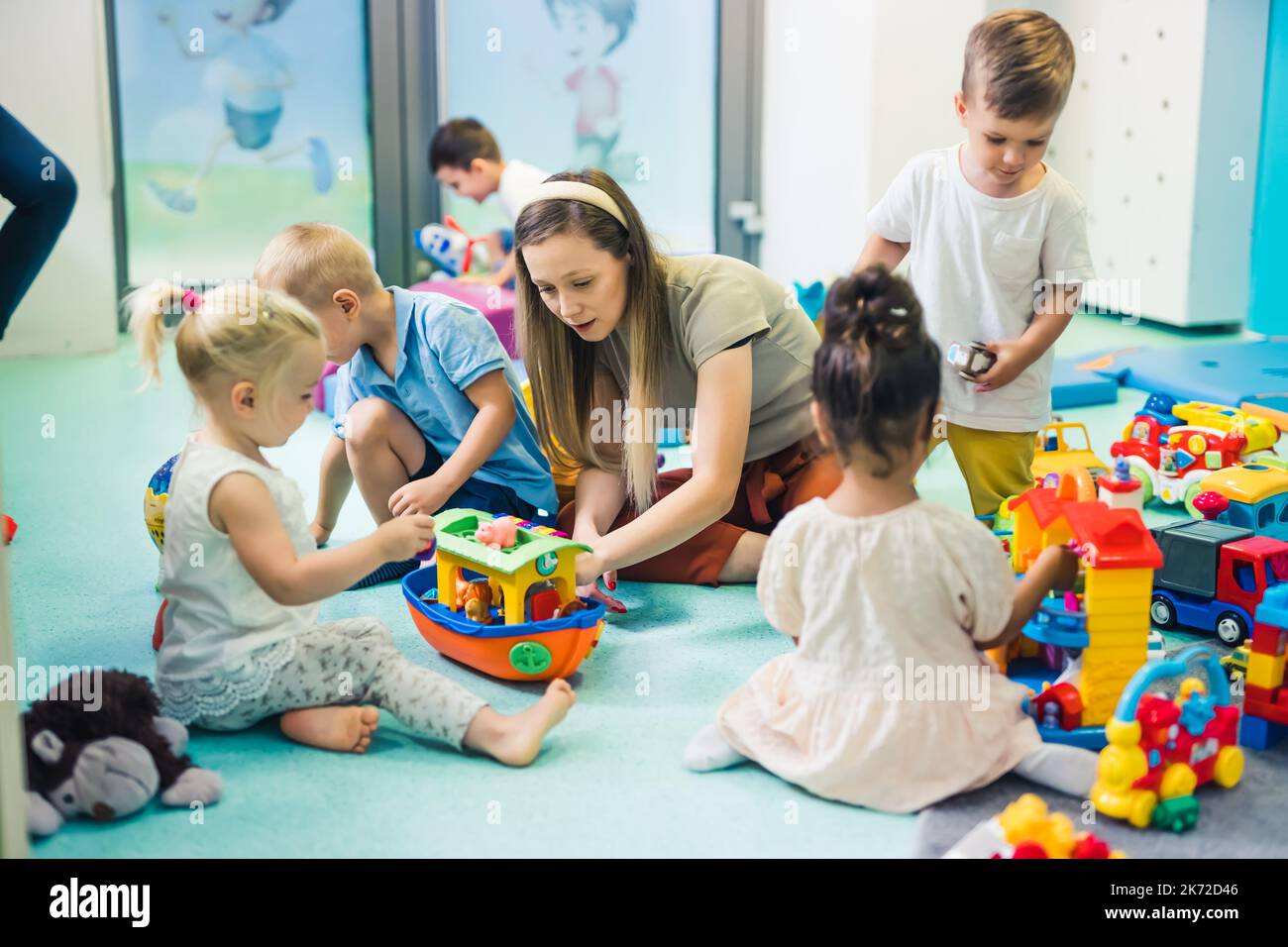 blond Caucasian teacher helping kids to build things properly in the ...