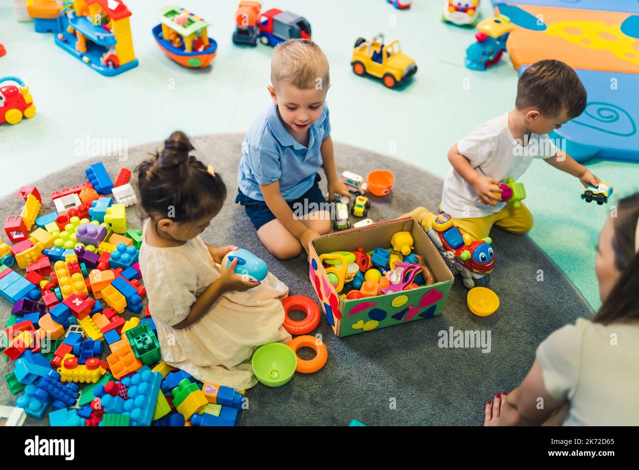 toddlers enjoying building blocks, cars, ships and other plastic toys ...