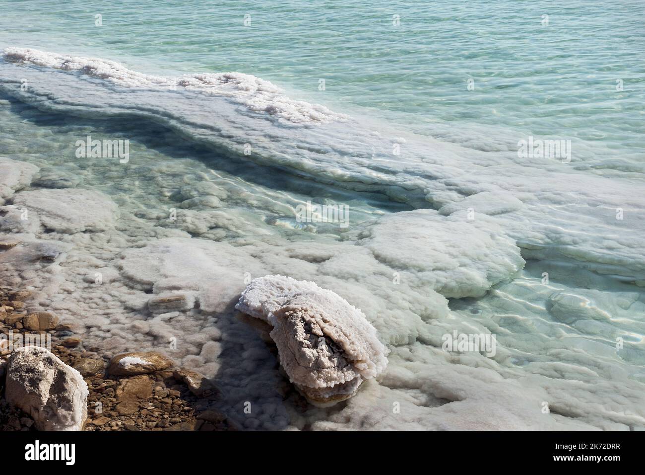 mineral salts chrystallizing around boulders in the industrial evaporation pond area of the Dead ...