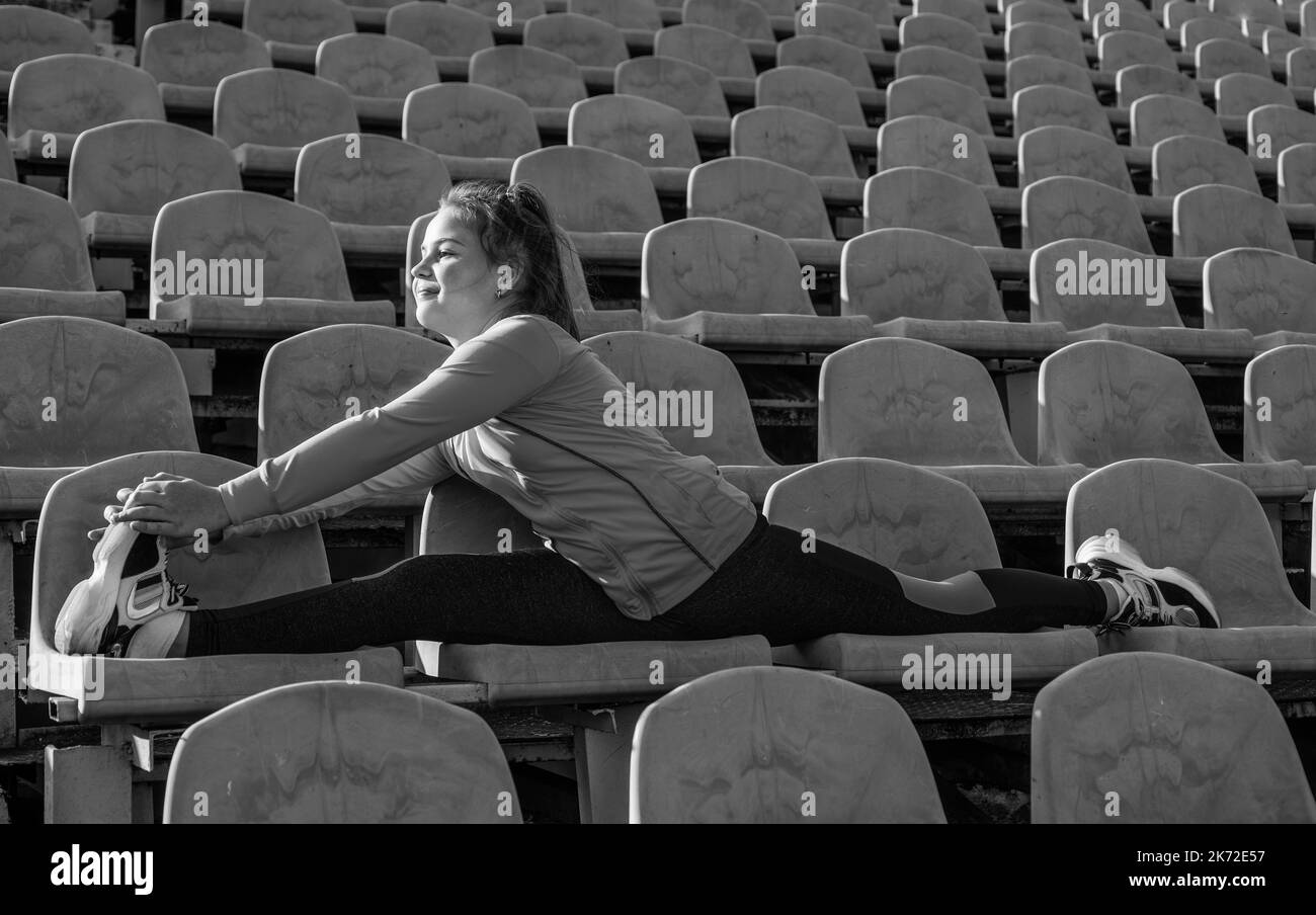 Flexible girl child in sportswear do splits stretching legs on stadium ...