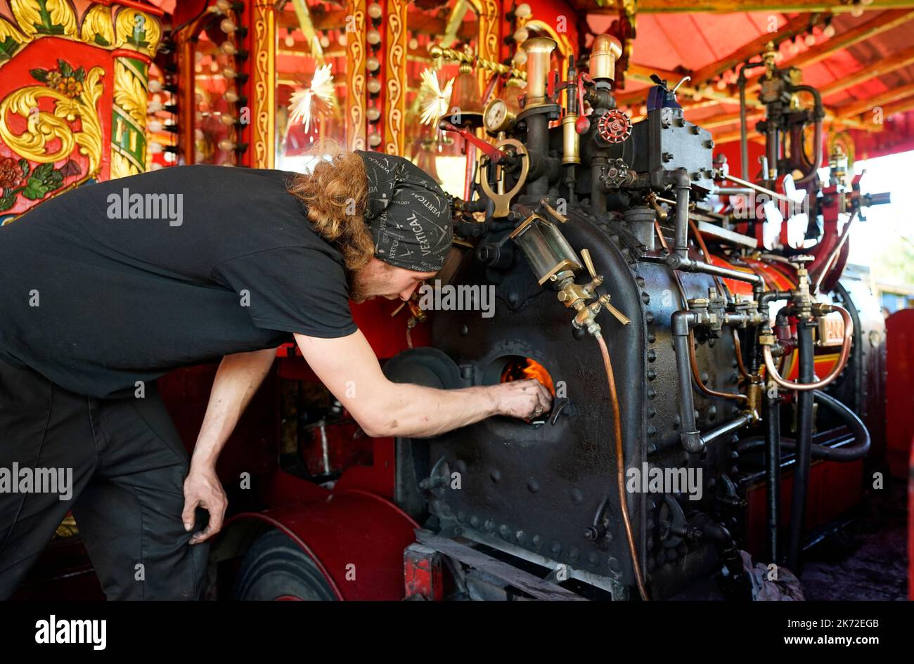 A member of the Carters Steam Fair places coal into the steam engine on ...
