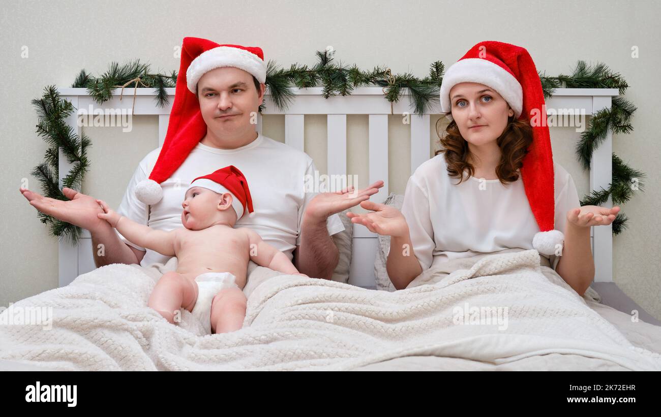 Husband and wife with baby shrug in bed decorated for christmas and new ...