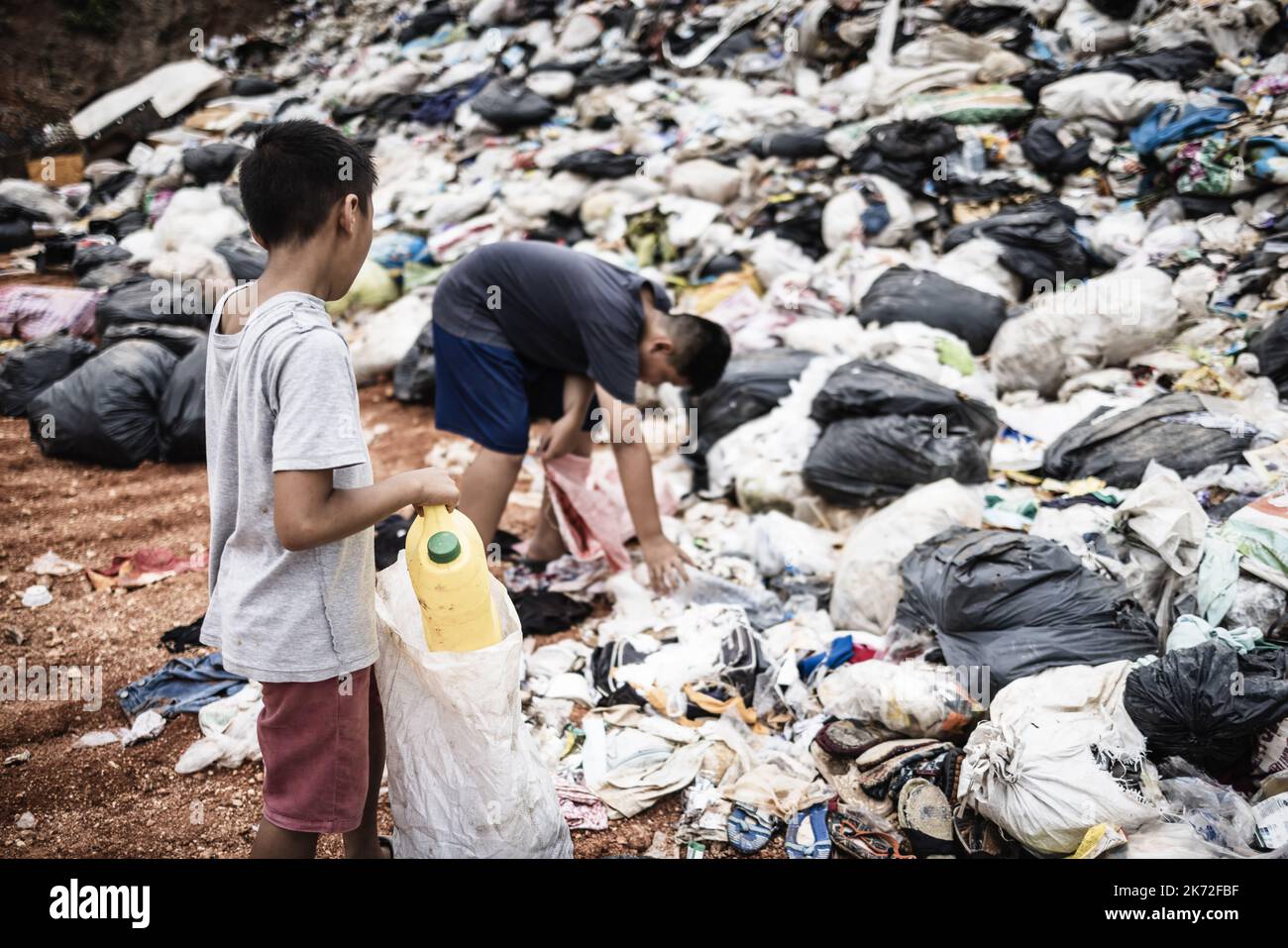 A young poor Indian boy collection waste plastic bottles in his sack to ...