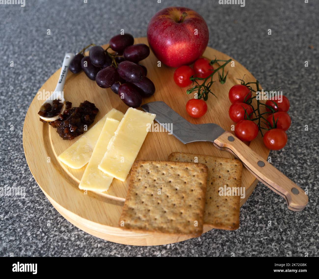 A cheese chopping board and cheese knife with sliced cheese, cherry ...