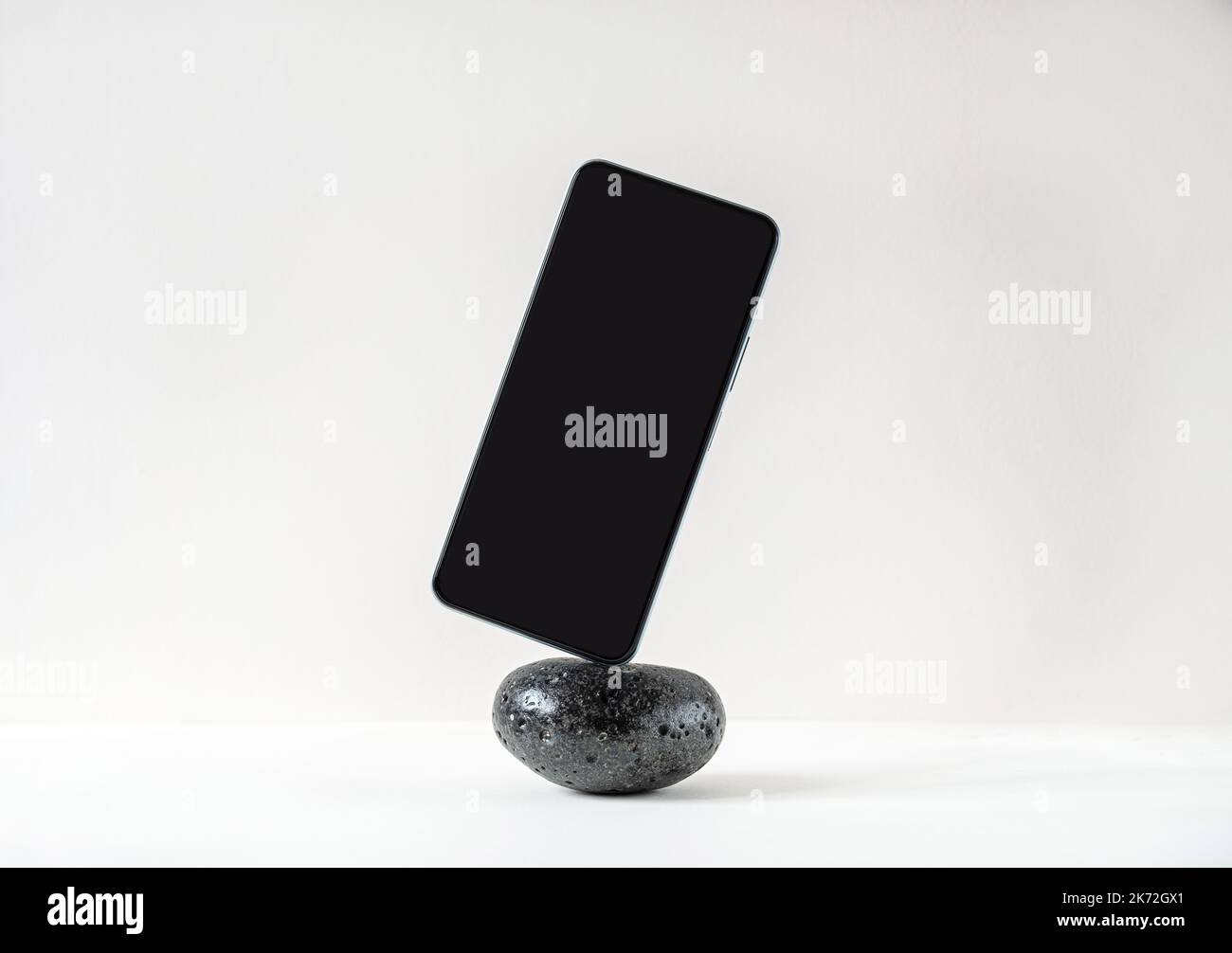 Composition of modern mobile phone with empty screen balancing on black ...